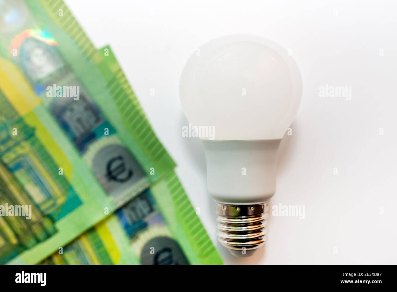 One LED bulb and 100 euro bills on white light background Stock Photo ...