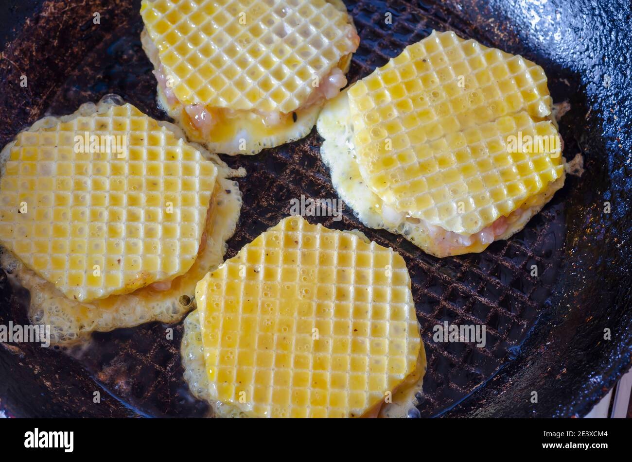 Traditional morning meal. Frying raw brizoles in waffle crusts ...