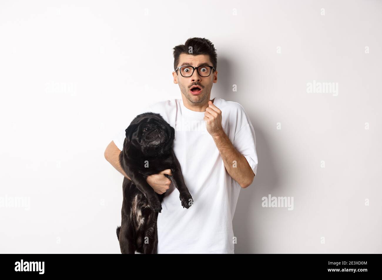Scared hipster hugging his cute black puppy and staring at camera ...