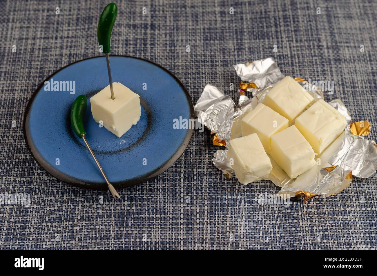 Processed cheese sliced into portions and skewers with a blue saucer on ...