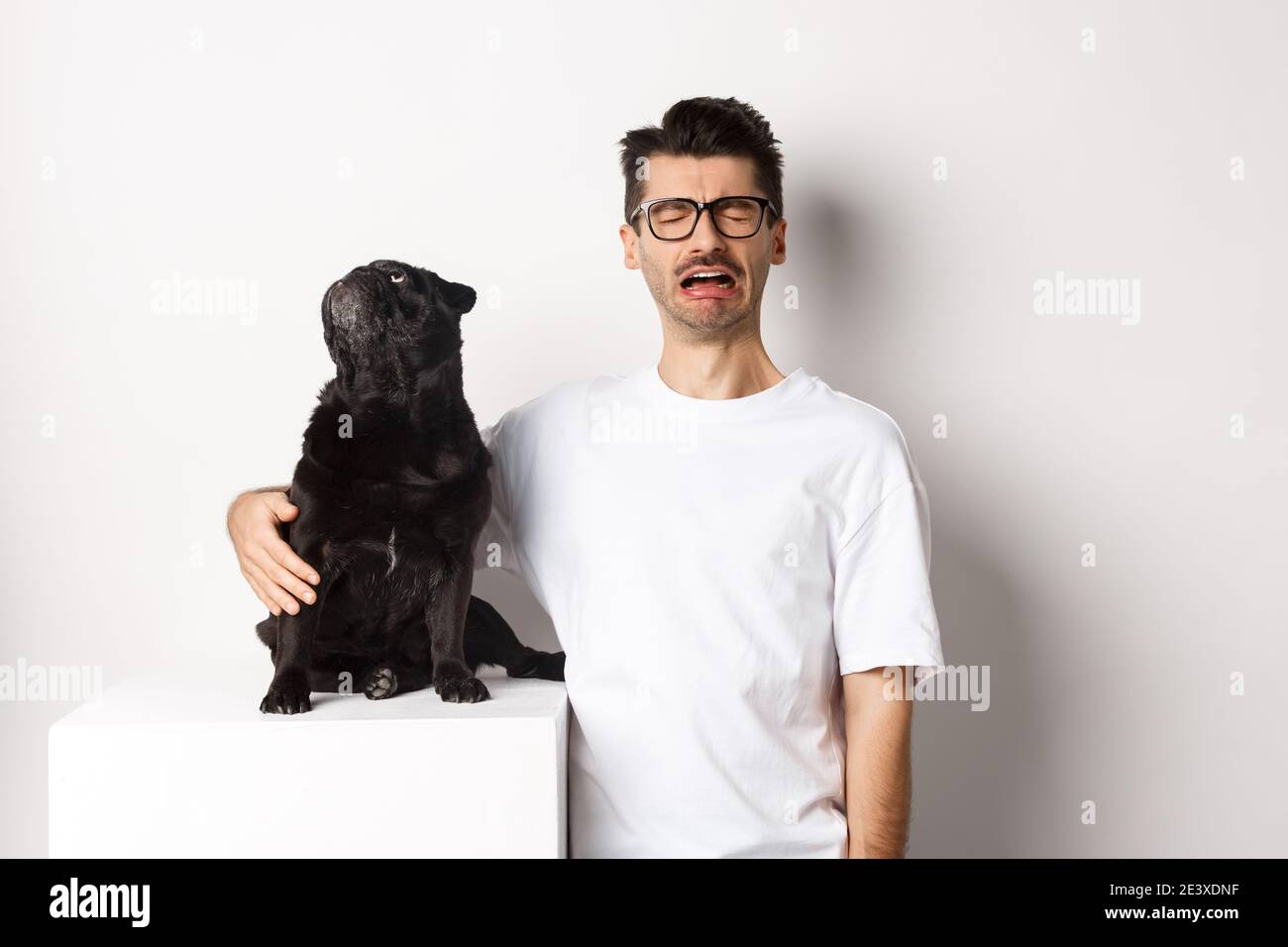 Image of sad crying man hugging his cute black pug, dog looking curious ...