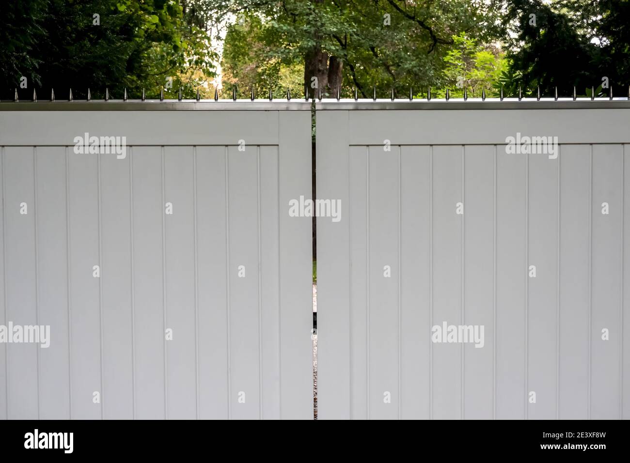 white-gray wooden gate with metal strip and spikes to prevent climbing ...