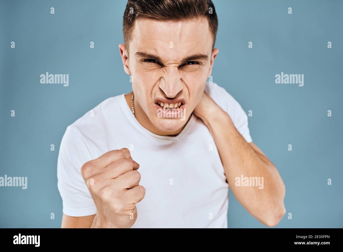 emotional displeased man cropped view white t-shirt blue background ...