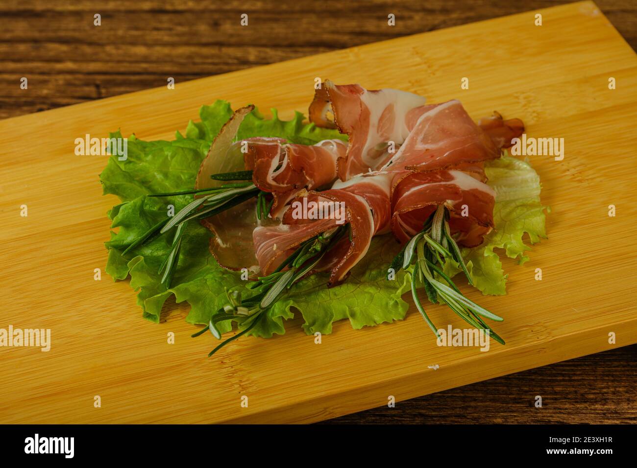 Sliced pork Jamon meat with rosemary Stock Photo - Alamy