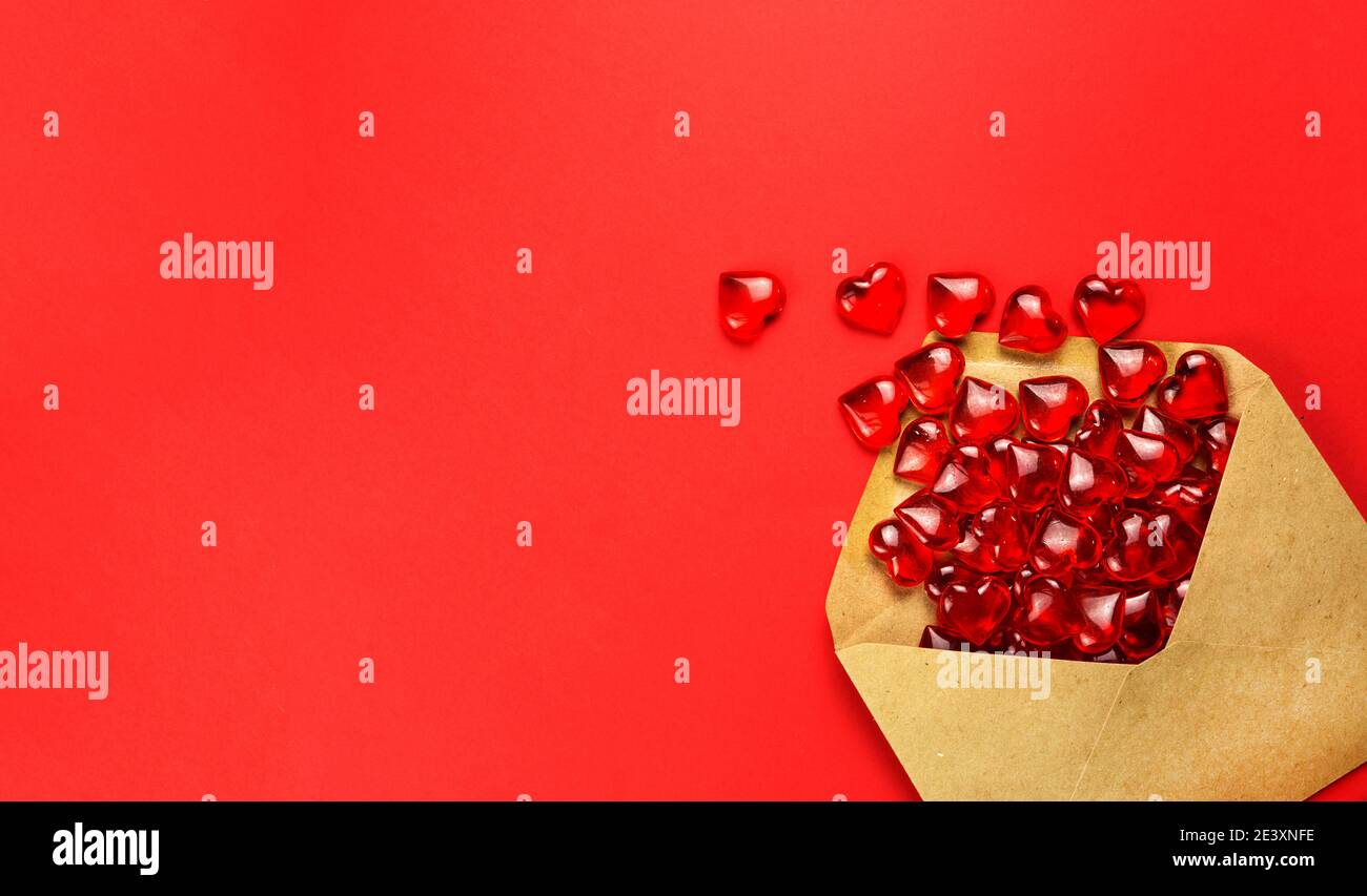 Glass hearts spill out of an open envelope on a red background ...