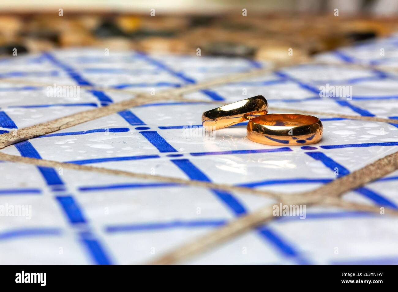 golden wedding rings over a table decorated with colored tiles Stock ...