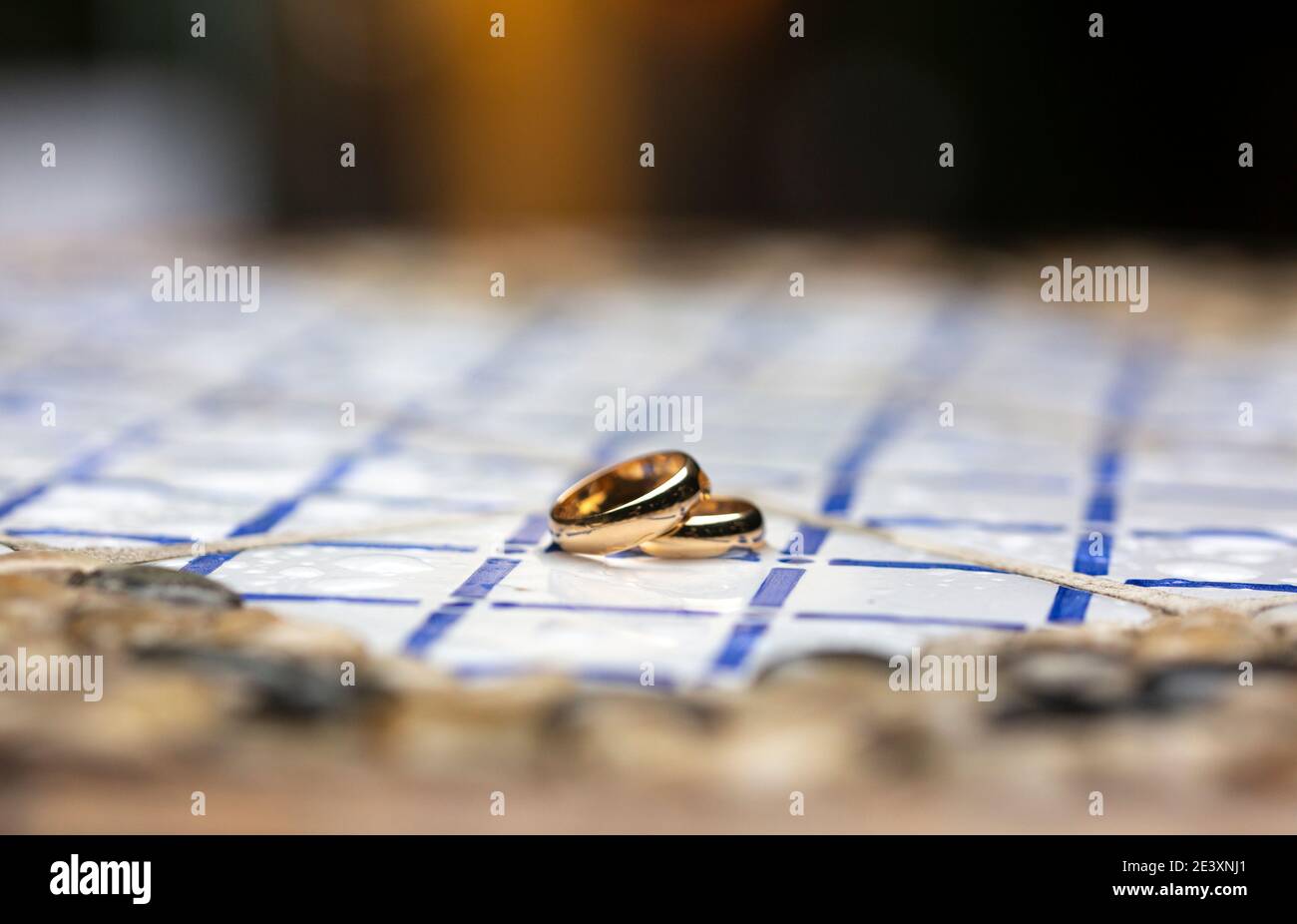 golden wedding rings over a table decorated with colored tiles Stock ...