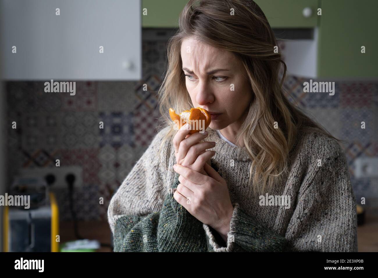 Sick woman trying to sense smell of fresh tangerine orange, has ...