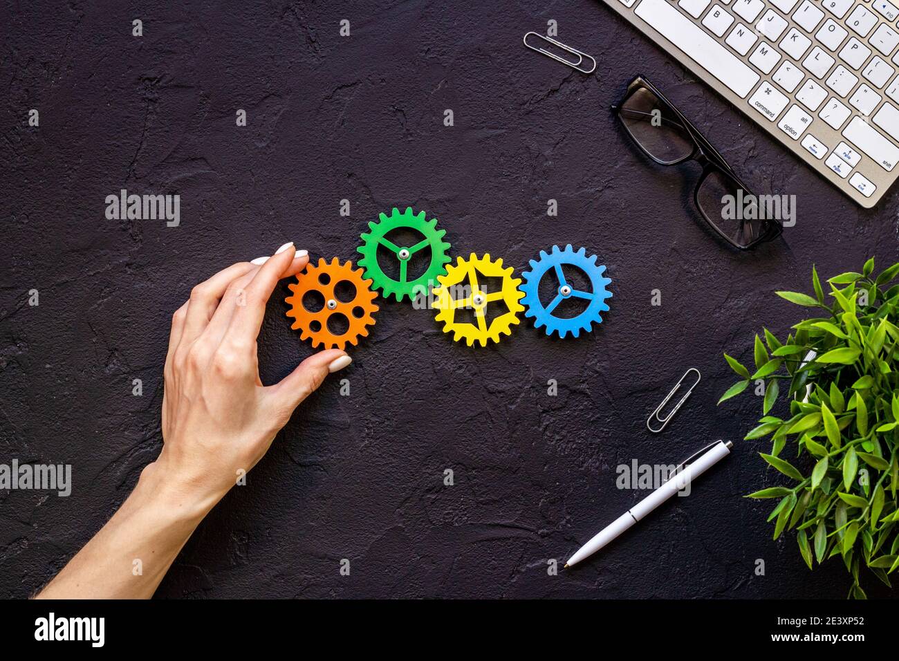 Hand puts a gear into one working mechanism. Teamwork and collaboration ...