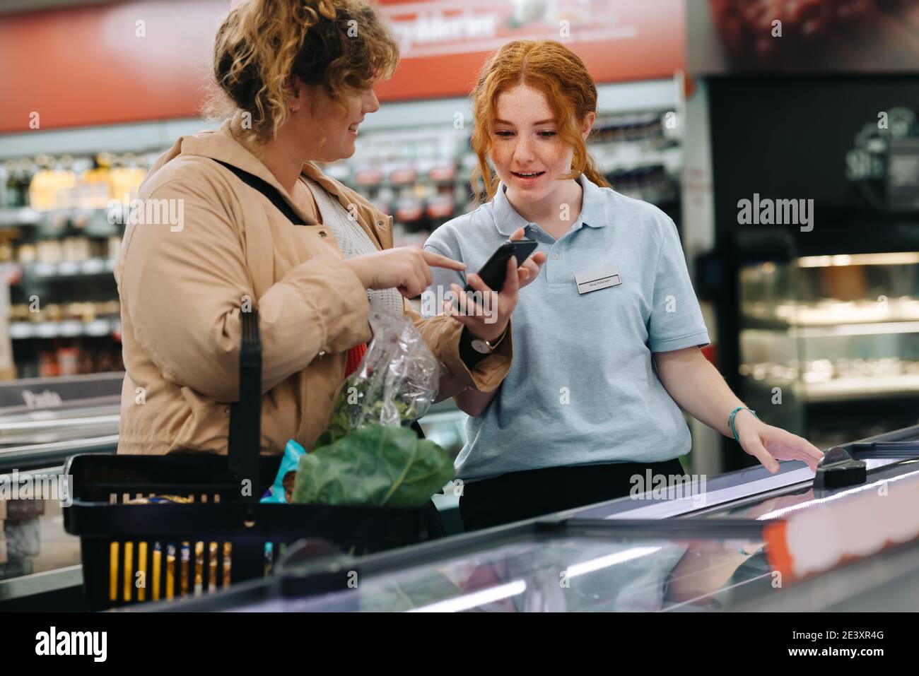 Grocery store worker assisting female shopper. Female customer showing ...