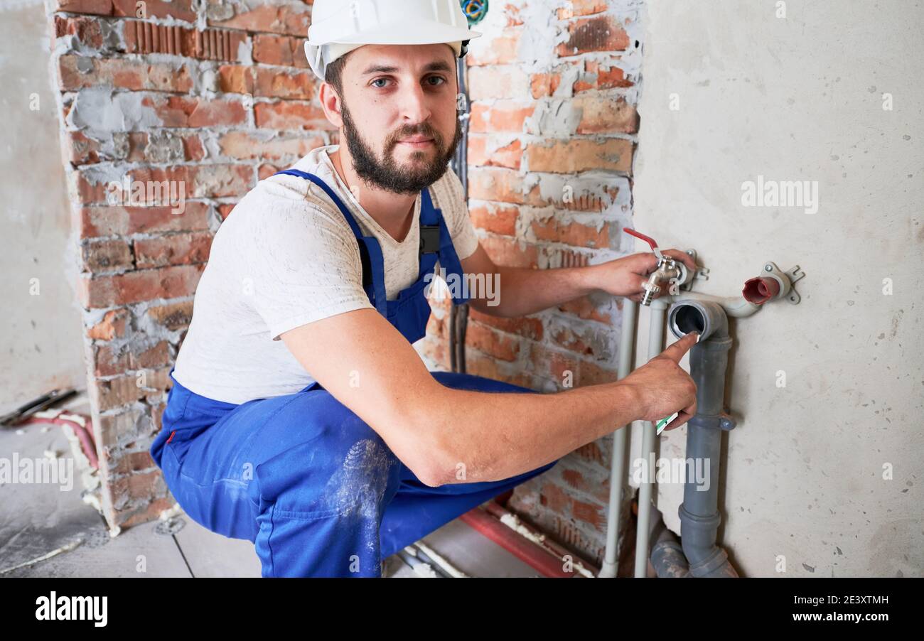 Handsome male worker in safety helmet looking at camera while applying ...