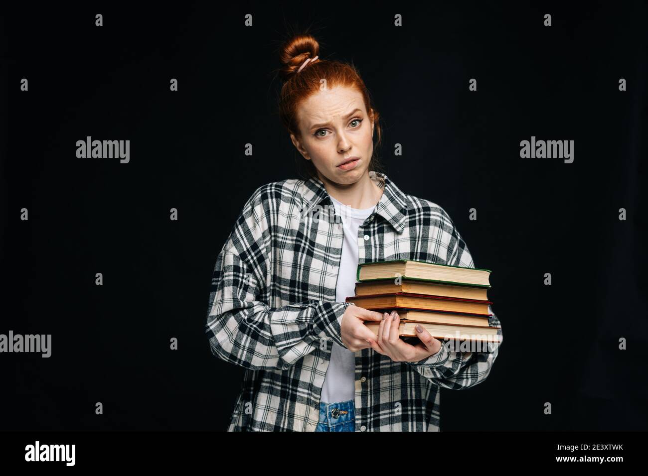 Confused sad young woman student holding books and looking at camera on ...
