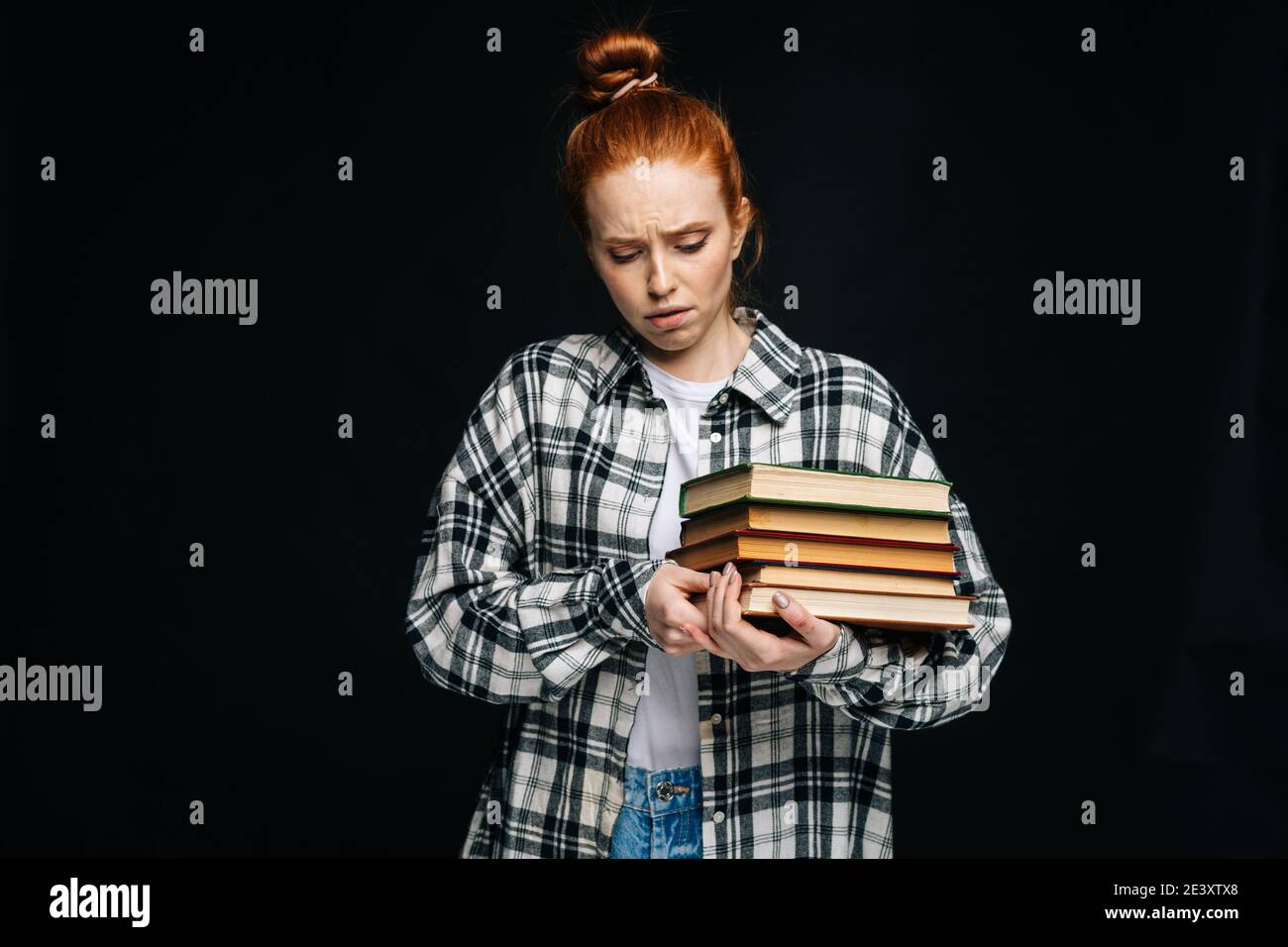 Confused young woman college student holding book and crying on black ...