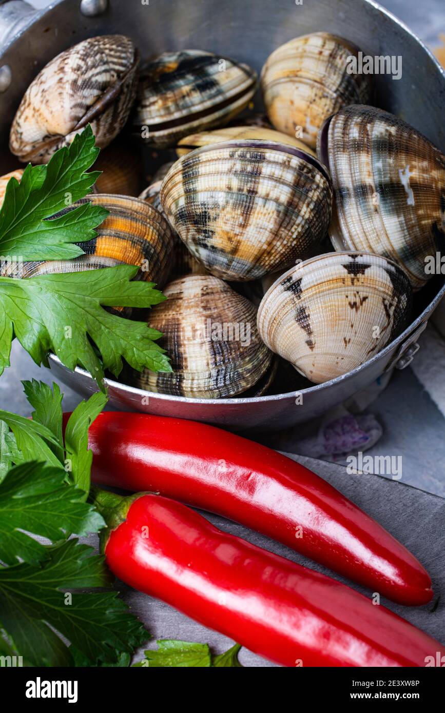 in the foreground, in an old colander, fresh clams with shell and red ...