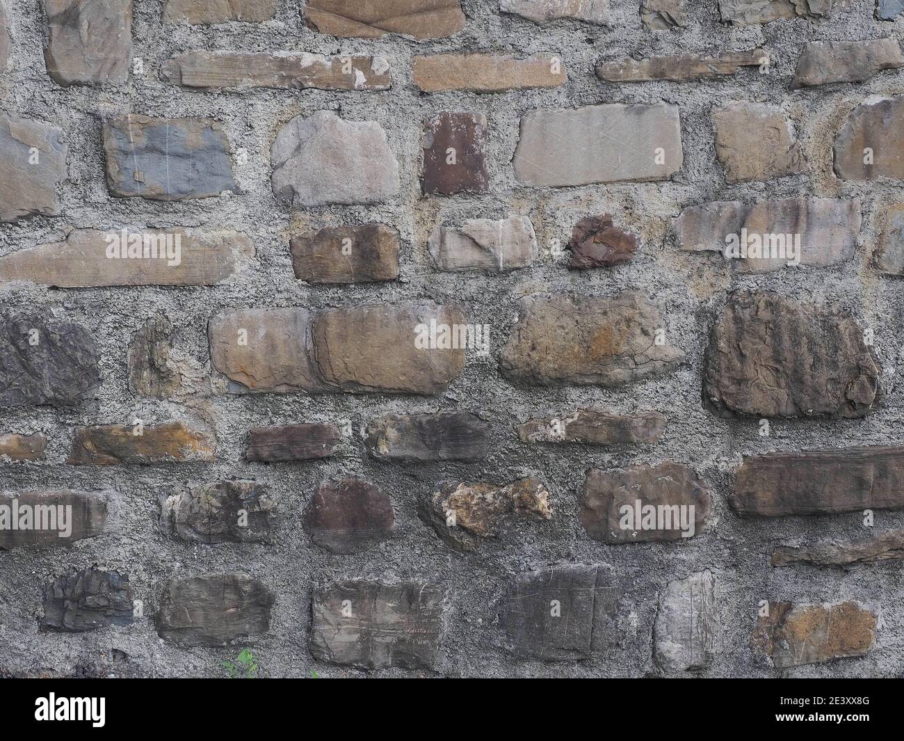 Wall with masonry of rough stone of various shapes and thick gray layer ...