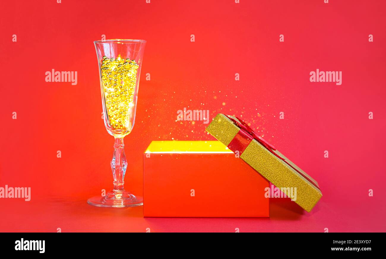 Open red gift box with golden glow and glitter inside and champagne ...