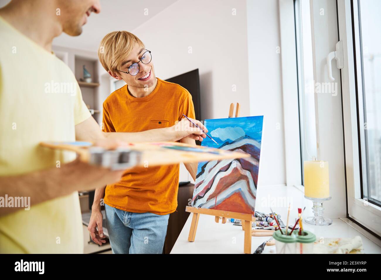 Male artist painting picture and spending time with boyfriend at home ...
