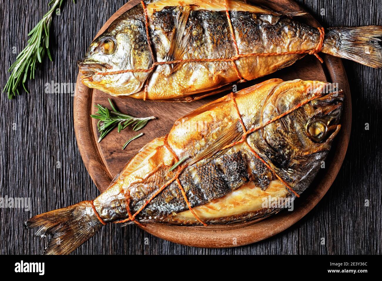 hot smoked gilt-head sea bream, orata fish on a wooden round cutting ...