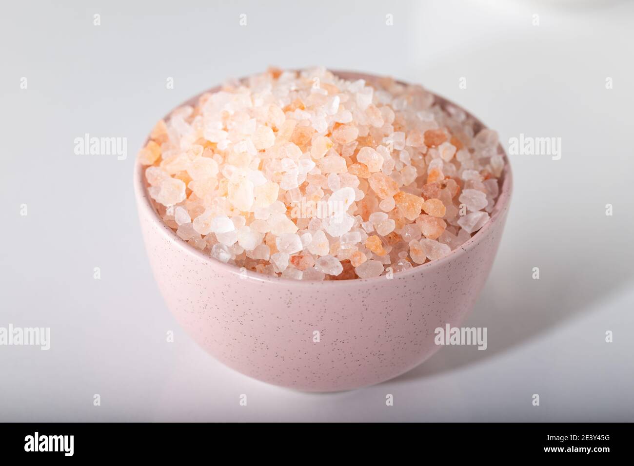 Pink rock salt in a pink bowl on a white background. Himalayan salt in ...