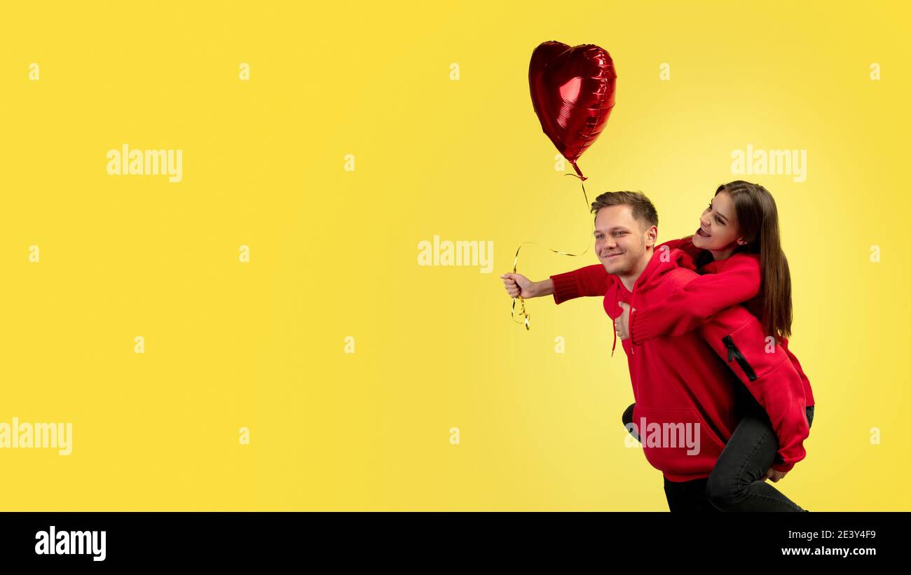 Piggyback, flyer. Beautiful couple in love on yellow studio background ...