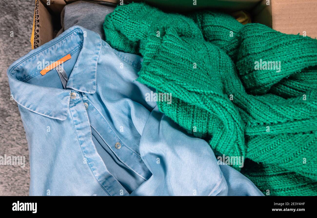Clothes in cardboard box. Clothing donation Stock Photo - Alamy