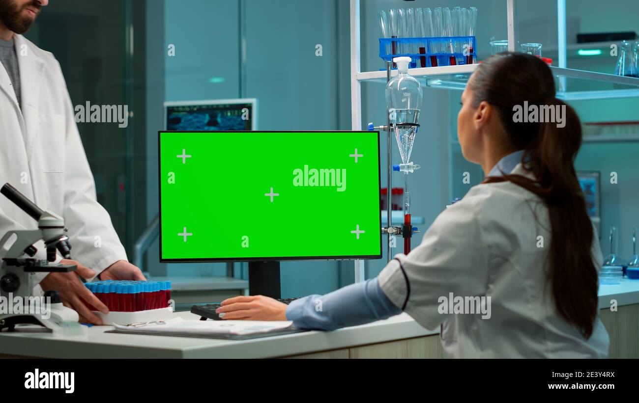 Scientist analysing blood sample and typing at computer with green ...