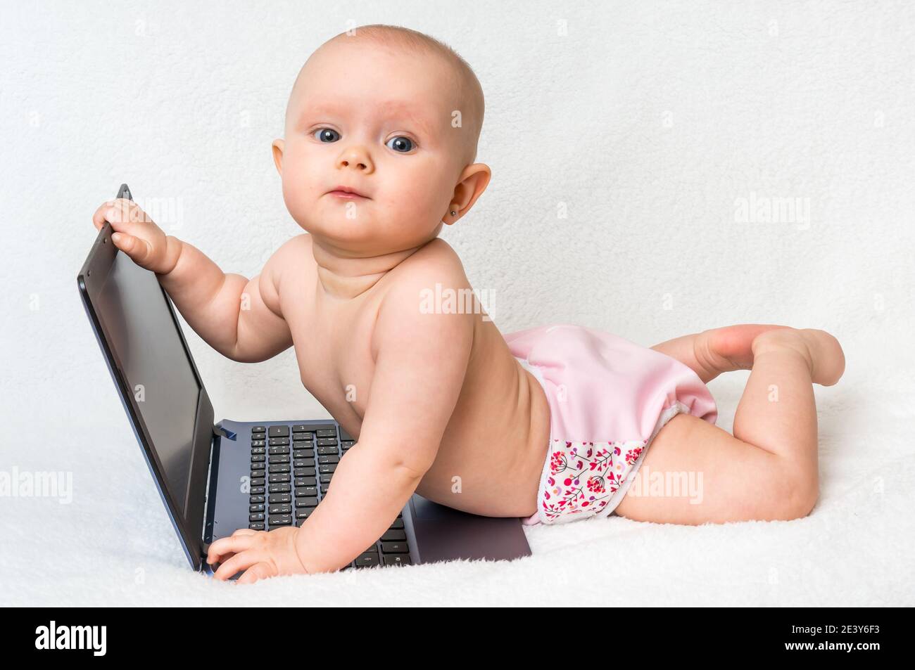 Cute baby girl in a diaper playing with laptop isolated on white ...
