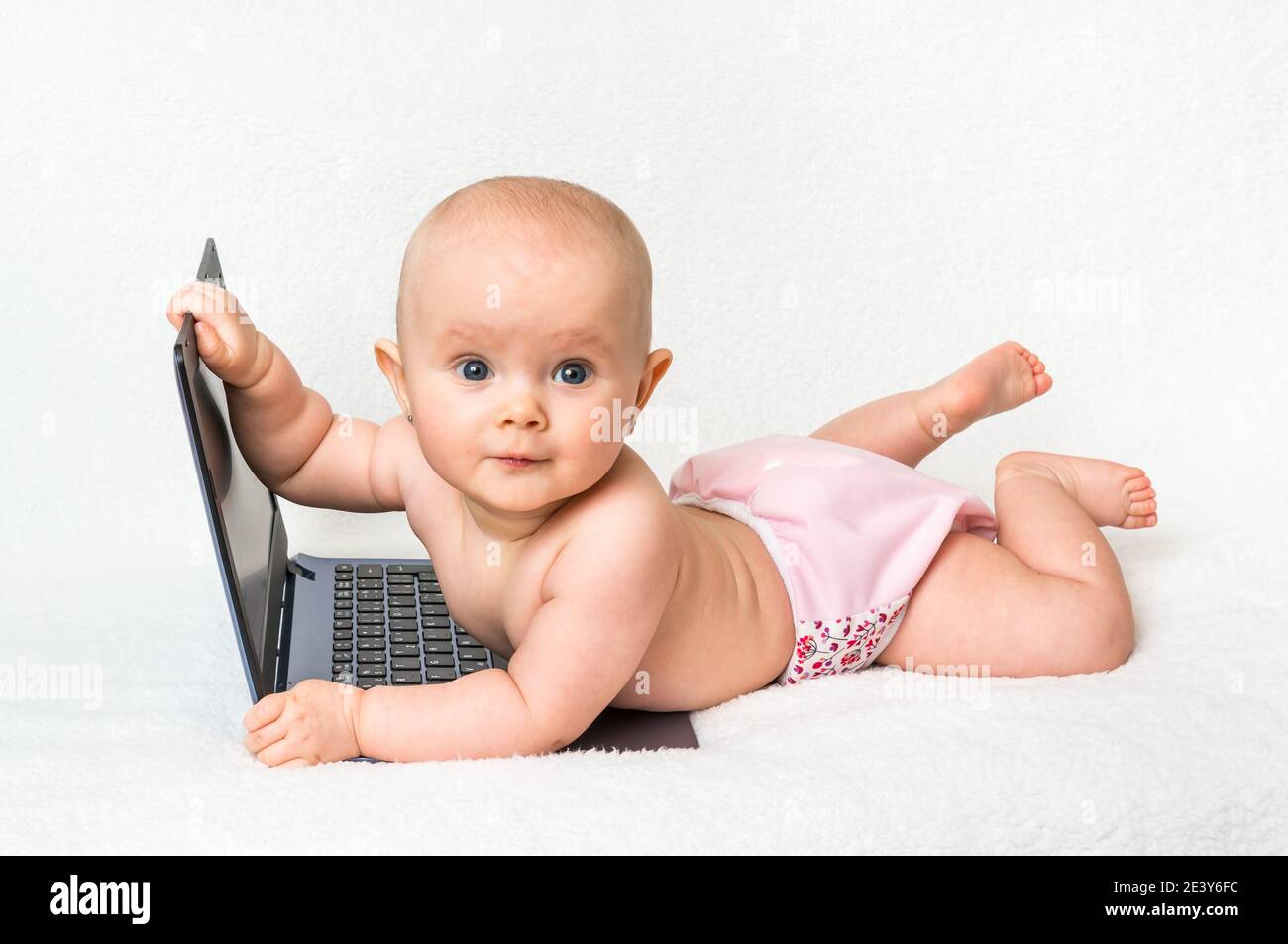 Cute baby girl in a diaper playing with laptop isolated on white ...