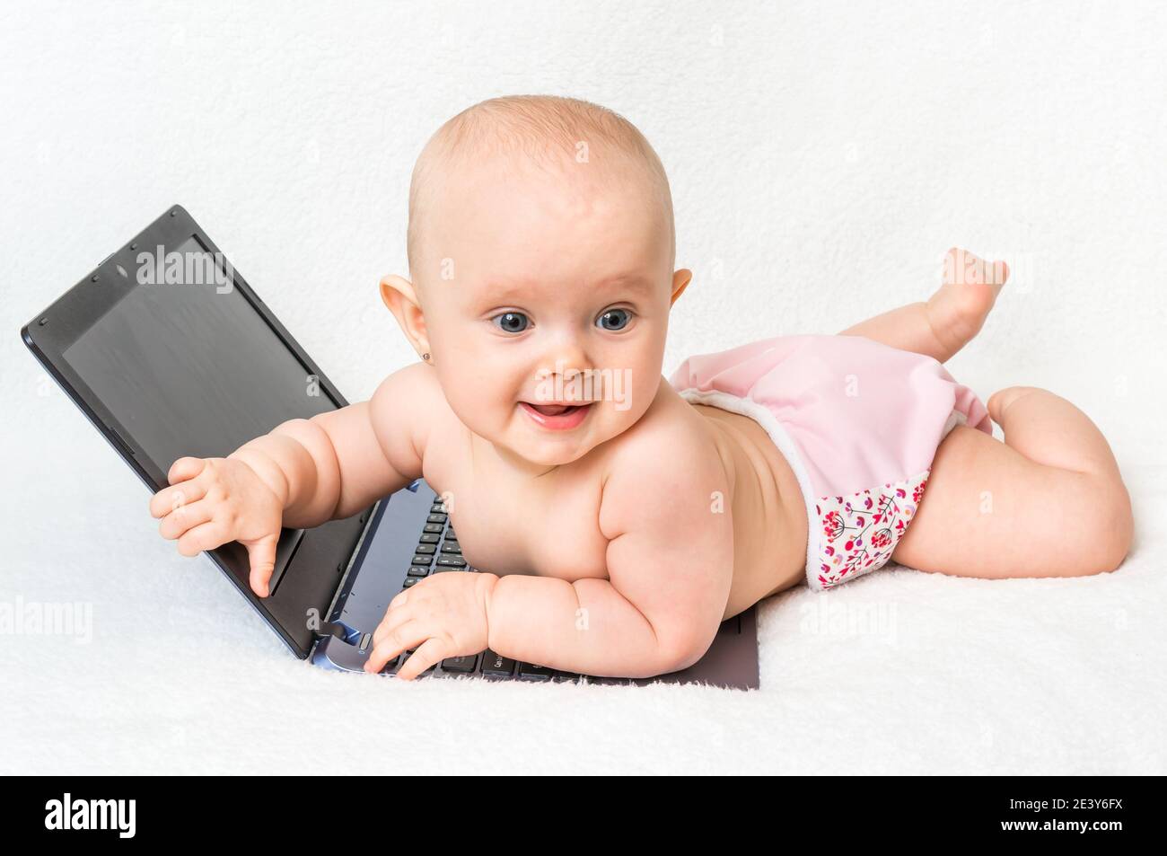 Cute baby girl in a diaper playing with laptop isolated on white ...