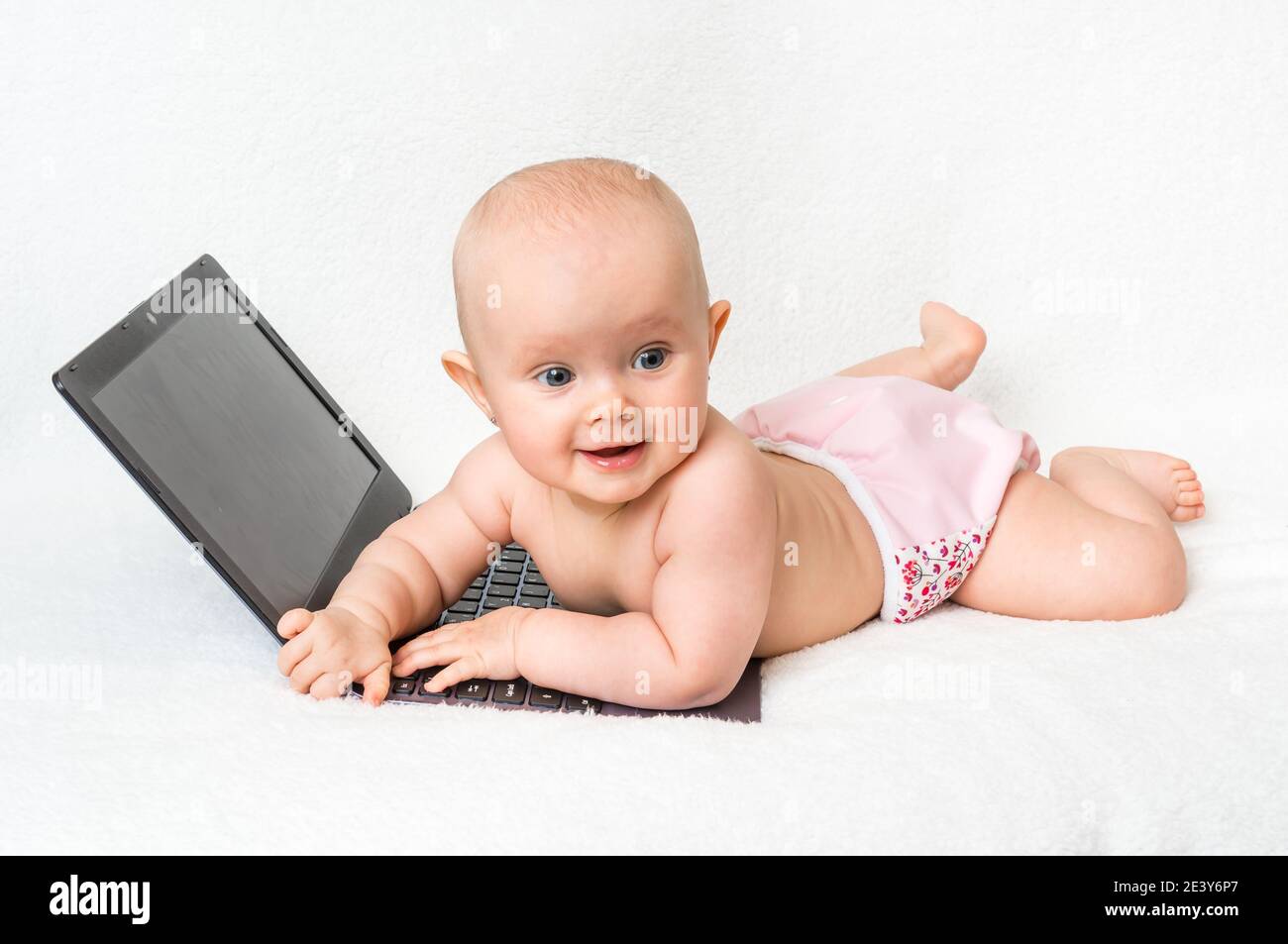 Cute baby girl in a diaper playing with laptop isolated on white ...