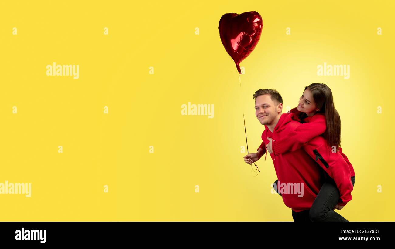 Piggyback, flyer. Beautiful couple in love on yellow studio background ...