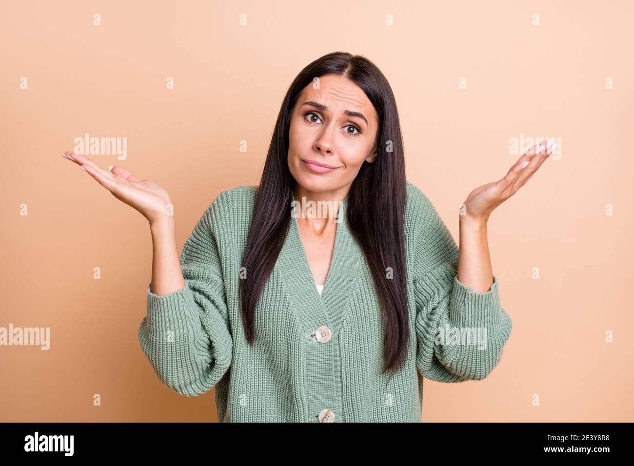 Portrait of sad unsure girl hands up shrug shoulders wear green sweater ...