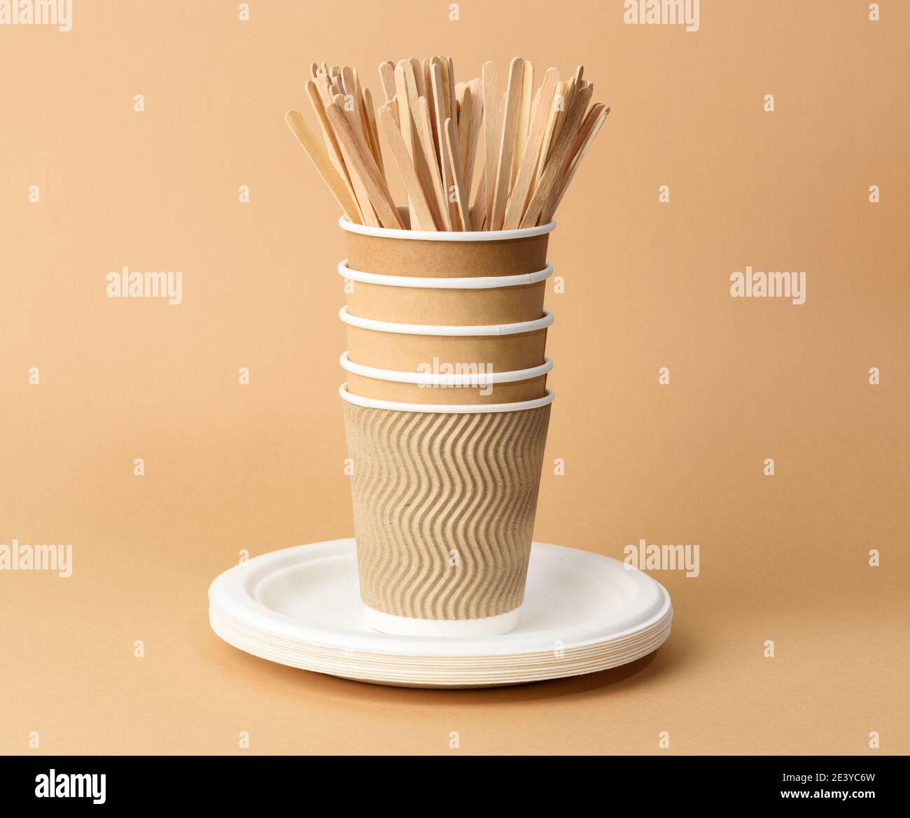 paper cup, white plates and wooden forks and knives on a brown ...