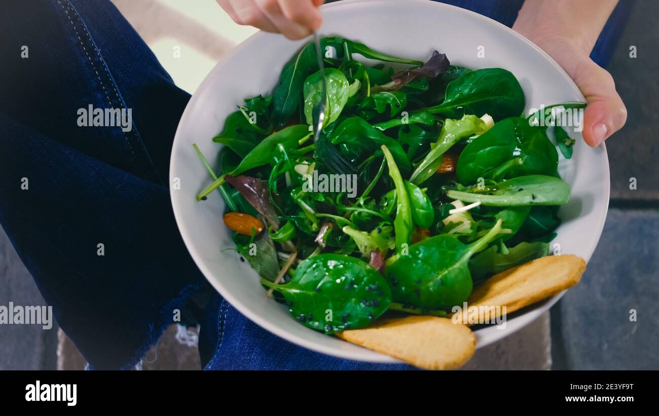 Eating salad, woman sitting eats a meal of salad. Fresh and light lunch ...