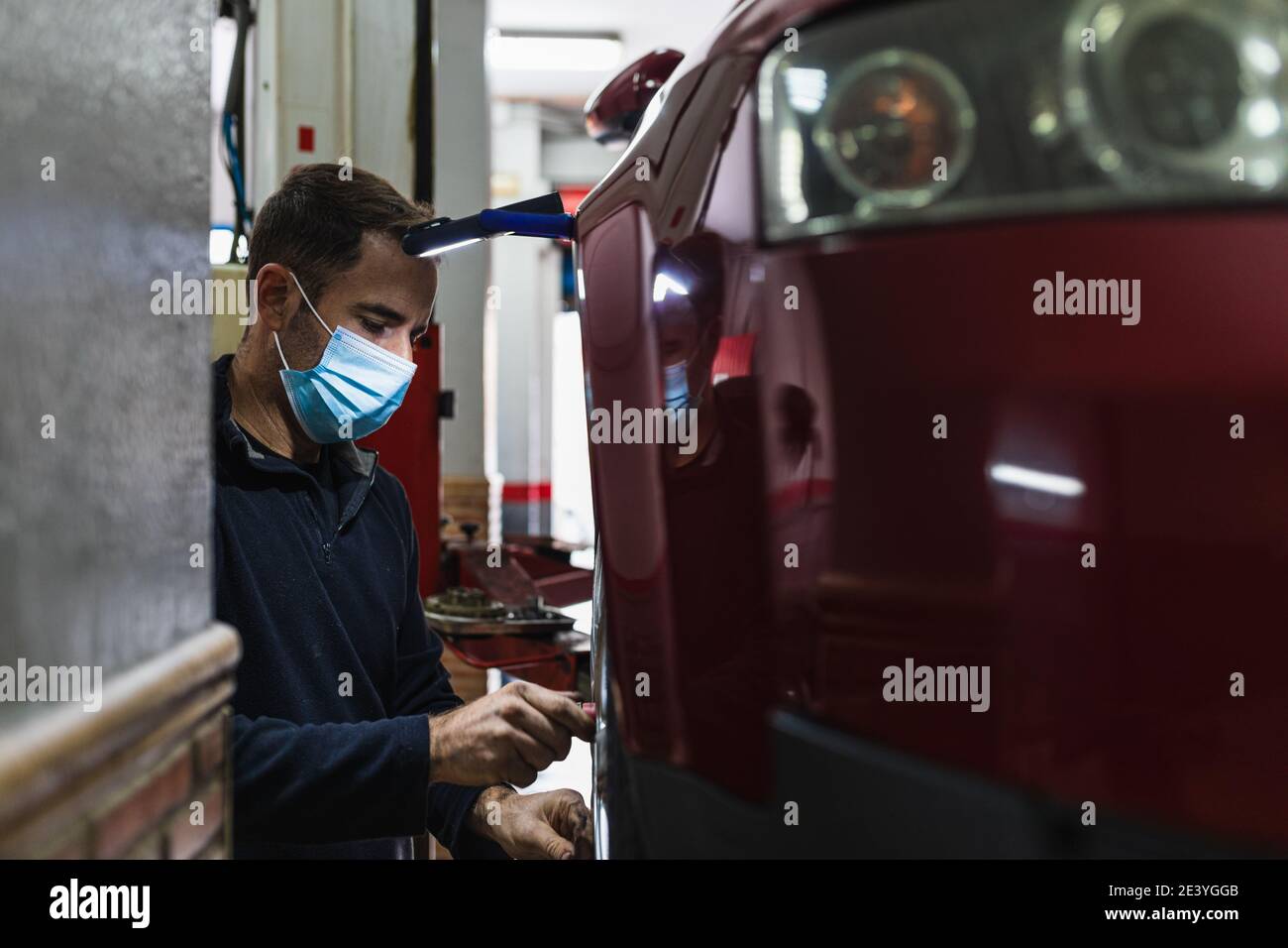 mechanic with mask repairing car wheel. Mechanical concept. Focus on ...