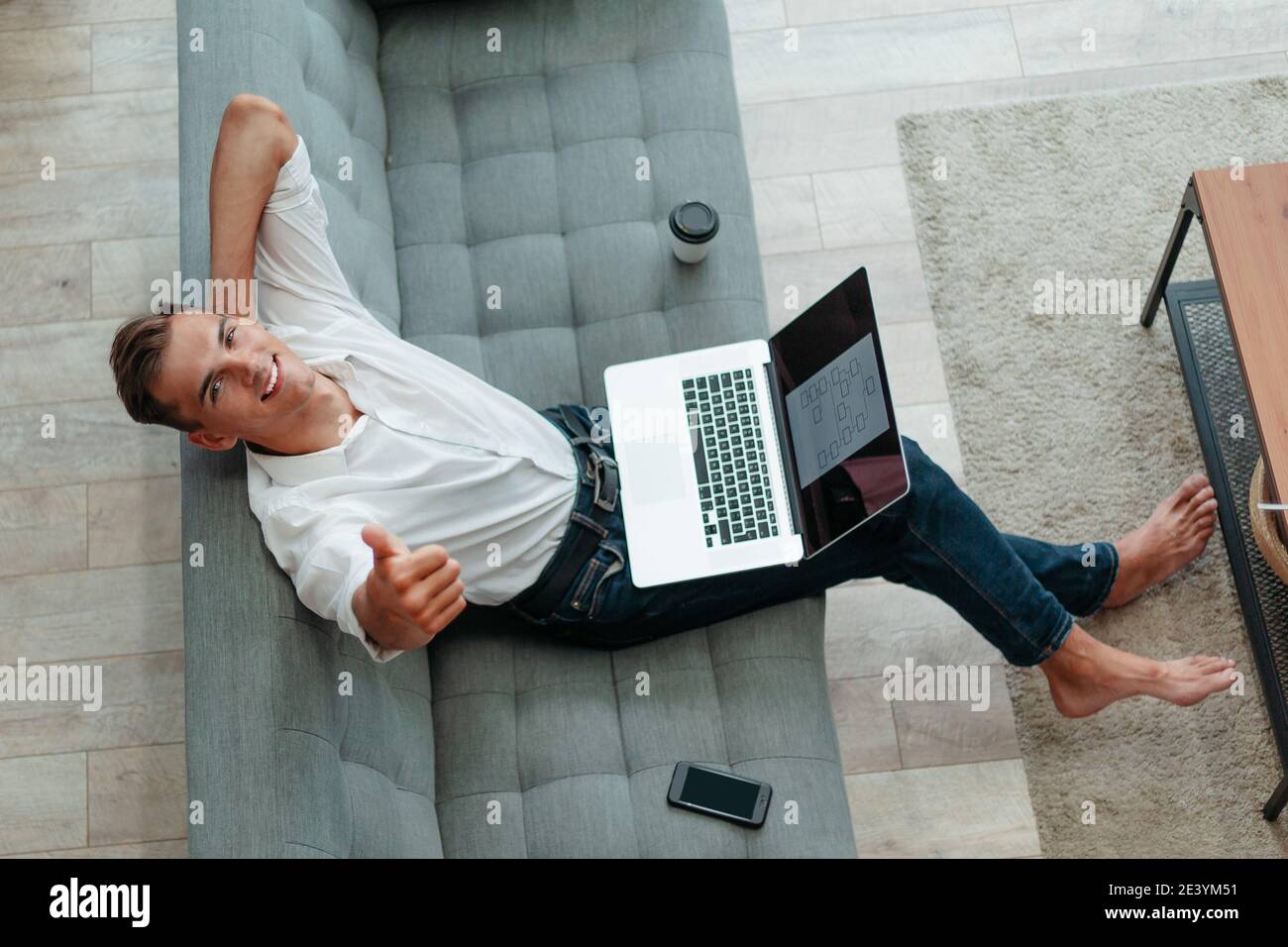 young man sitting on the couch and giving a thumbs up Stock Photo - Alamy