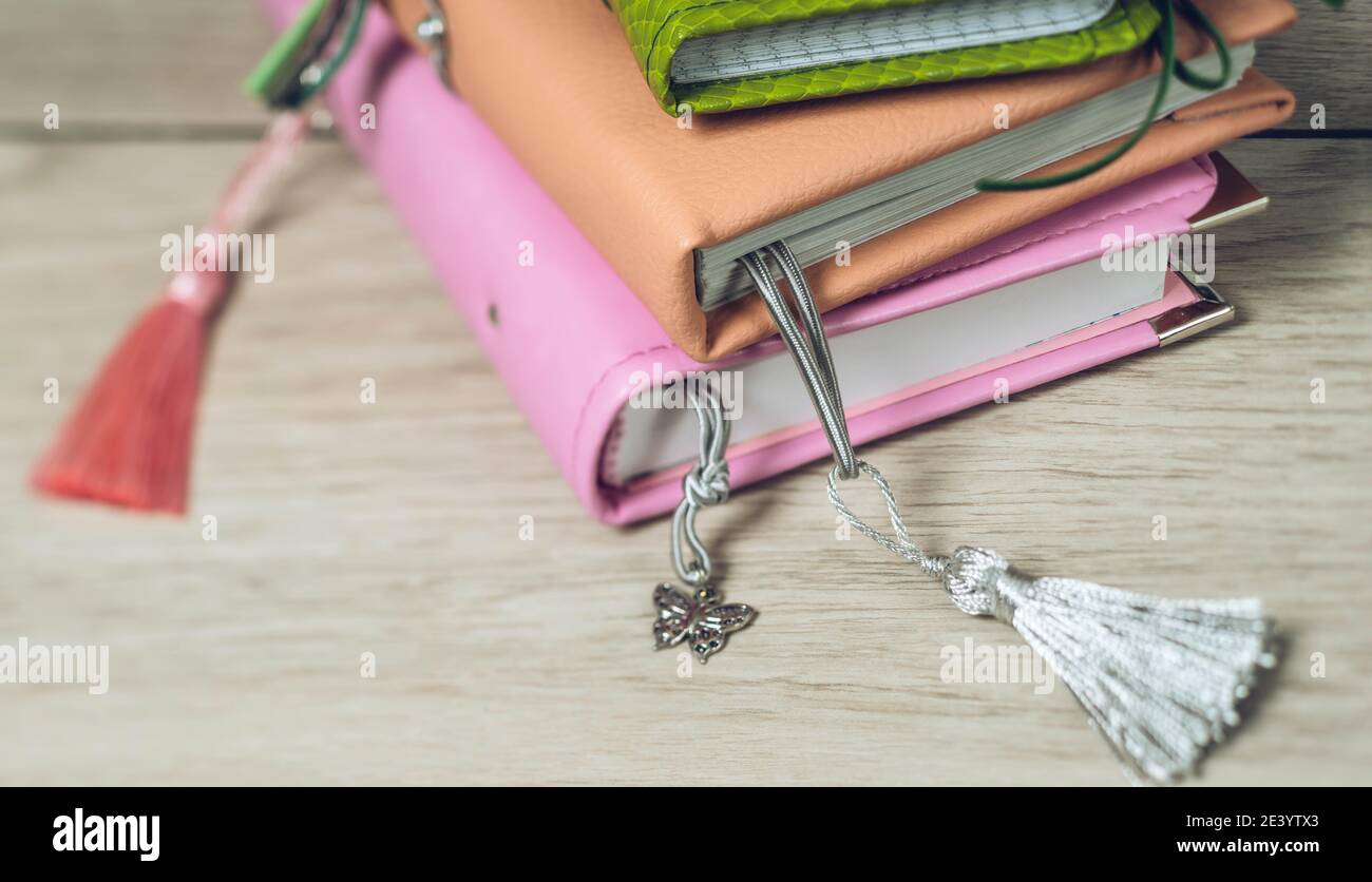Close-up of stack of cute pink and green closed notebooks. Wooden table ...
