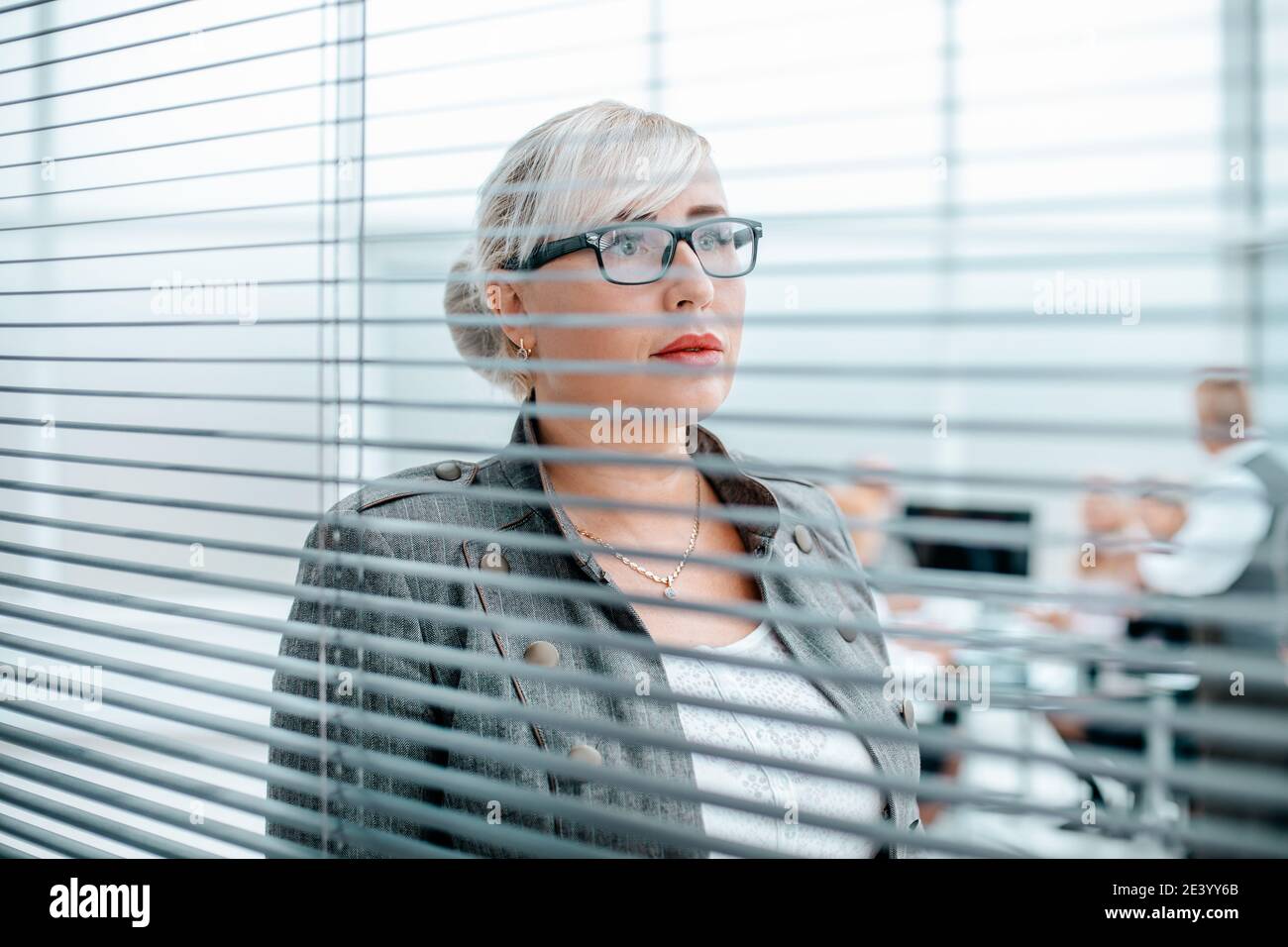 close up. serious business woman looking through office window Stock ...