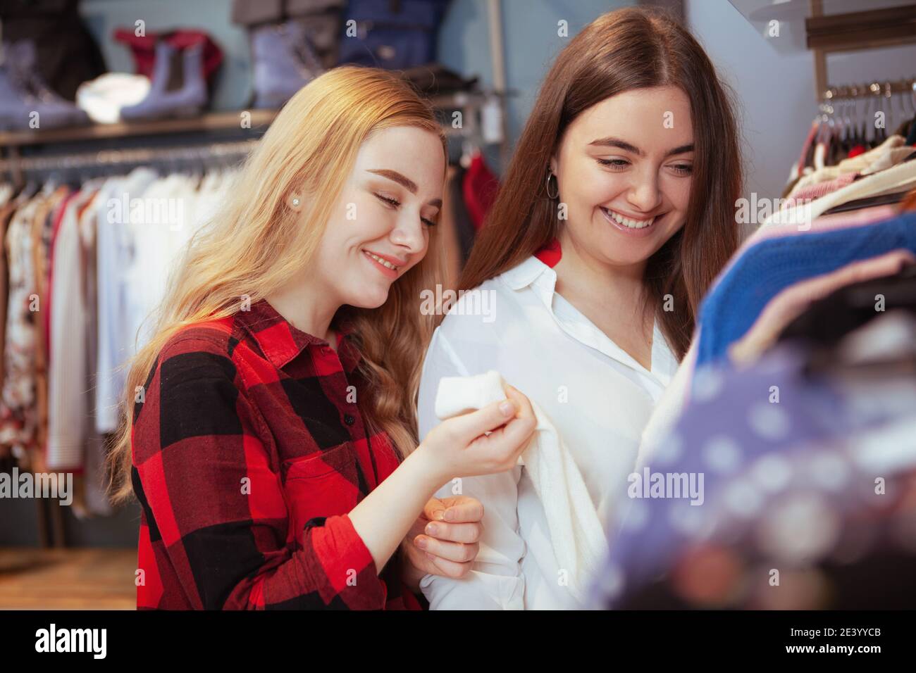 Happy female friends enjoying shopping for new clothes together. Lovely ...
