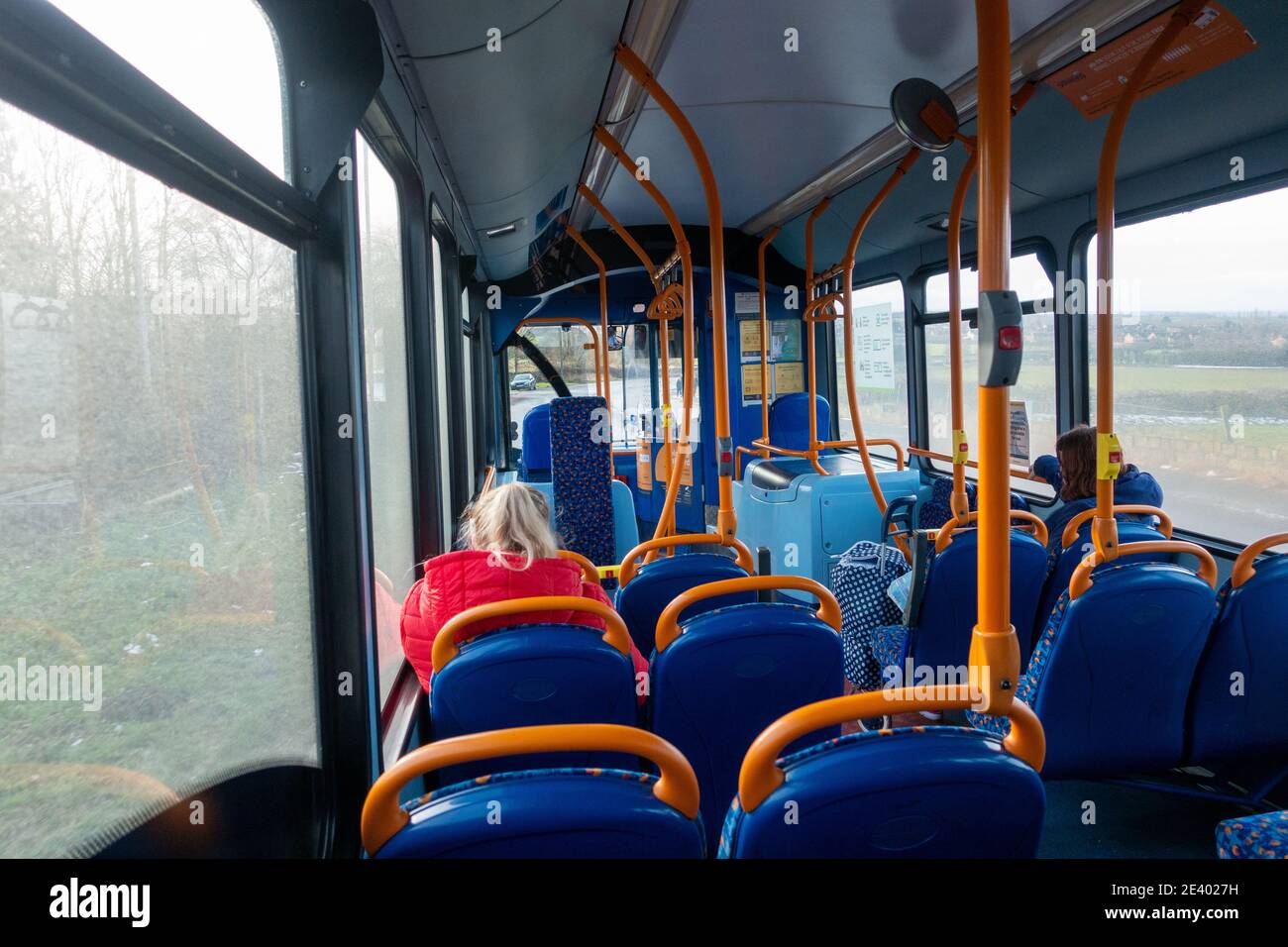 daylight interior of a bus and seating from the rear with the backs of ...