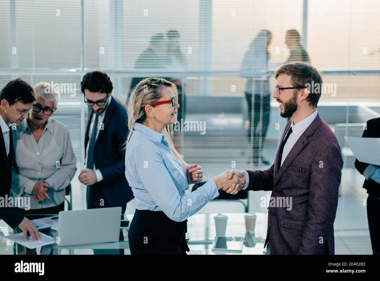 happy colleagues shaking hands with each other near the desktop Stock ...