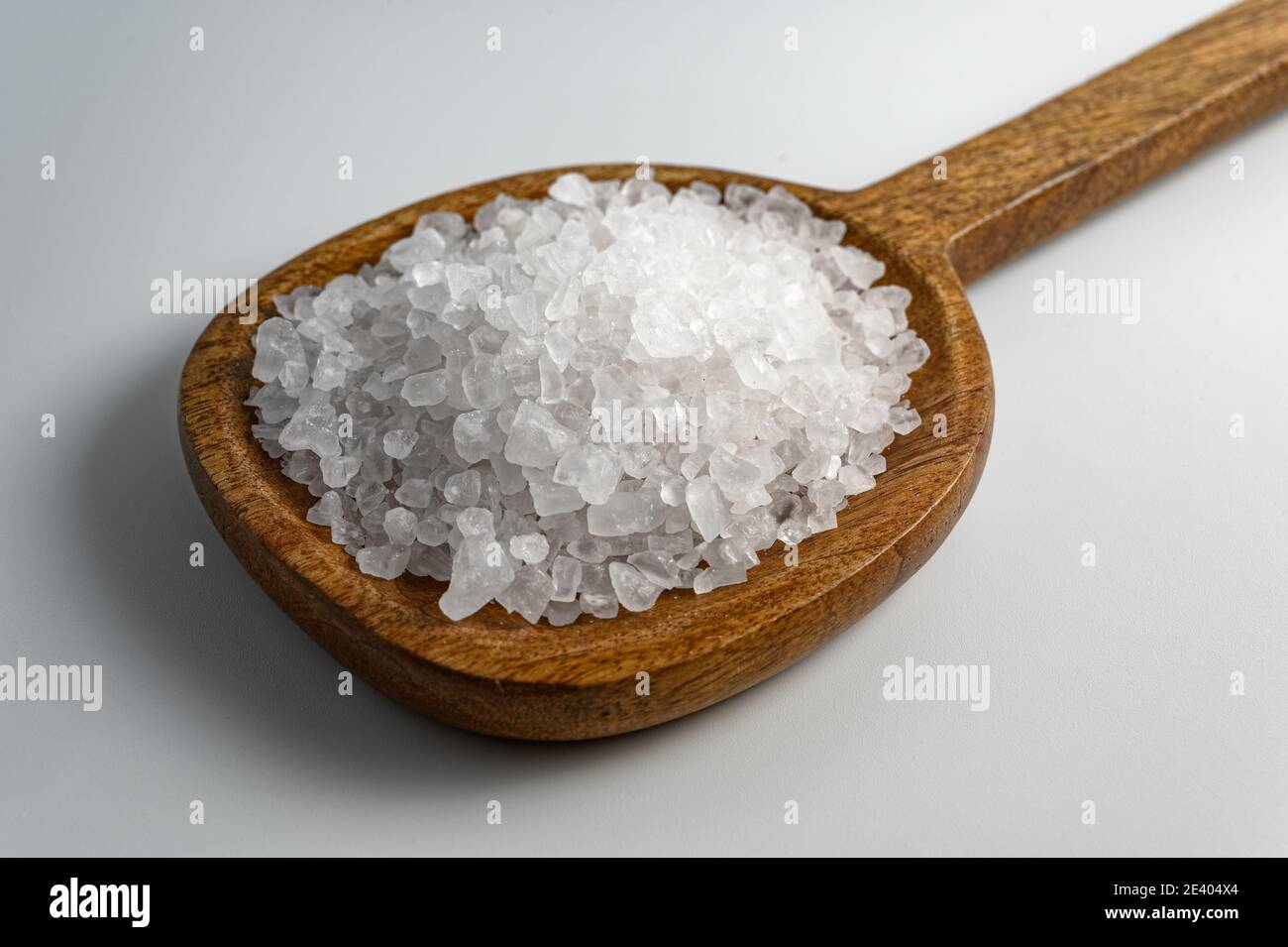 Sea salt in wooden spoon on white background Stock Photo - Alamy