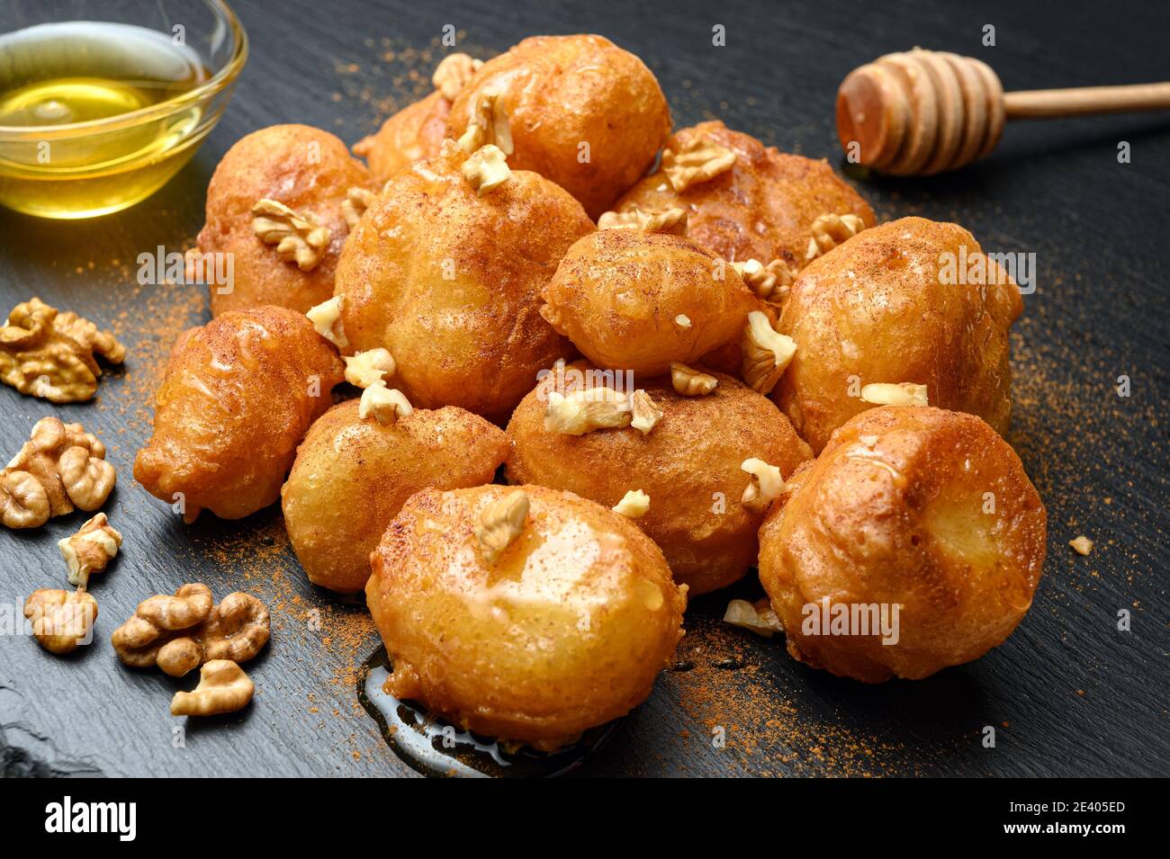 Homemade lokma served with honey, nuts and cinnamon on black dish Stock ...