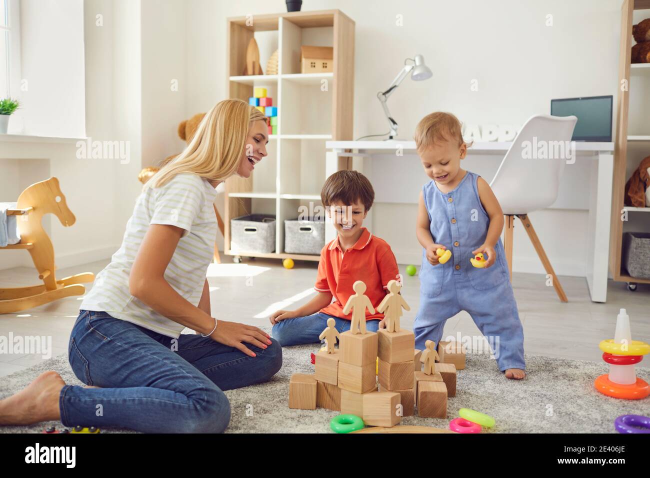 Happy family mother and two children building pyramid of wooden details ...