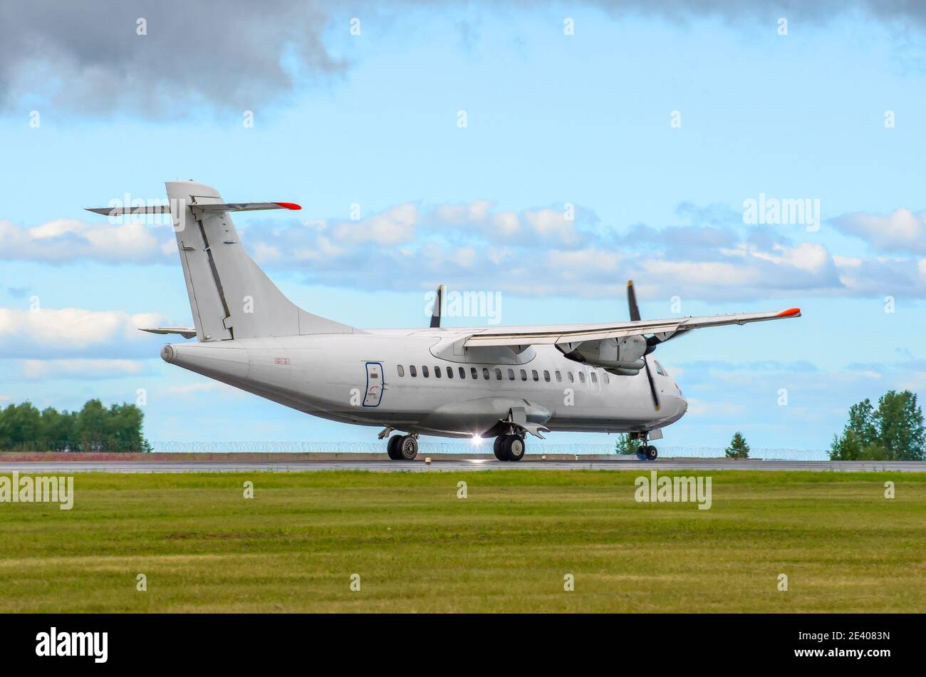 Passenger turboprop airplane landing the runway against the blue sky ...