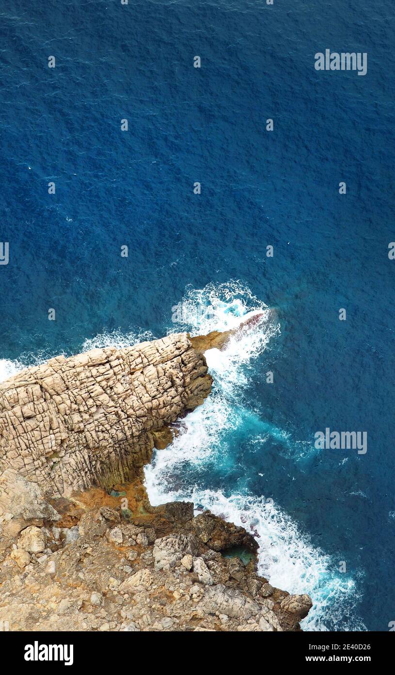 Rocky gray cliffs with moss, braking the waves of the deep blue sea ...