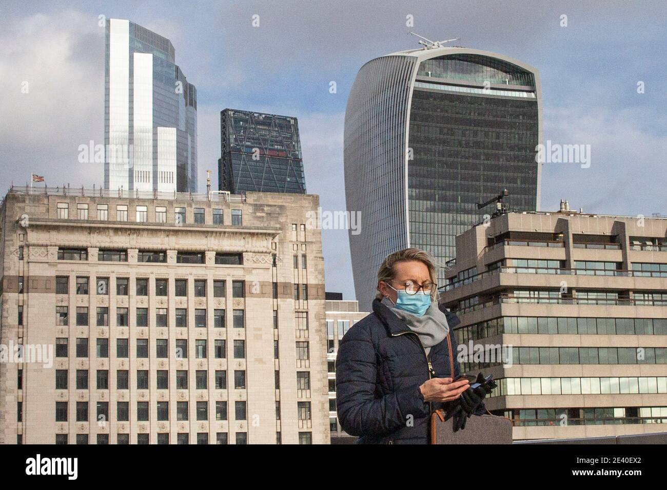 People wearing masks walk across London Bridge with Tower Bridge in the background during ...