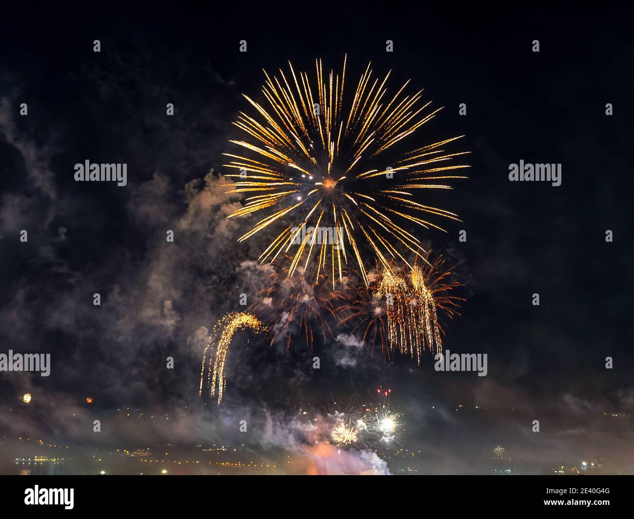 Bright firework sparkles in the dark sky. Small city celebrating with ...