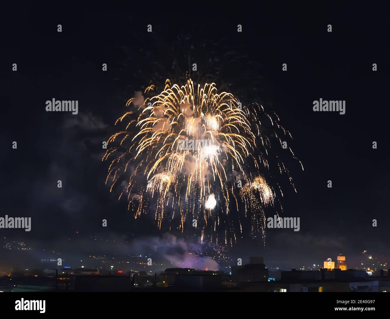 Bright firework lights in the dark sky. Small city celebrating with ...