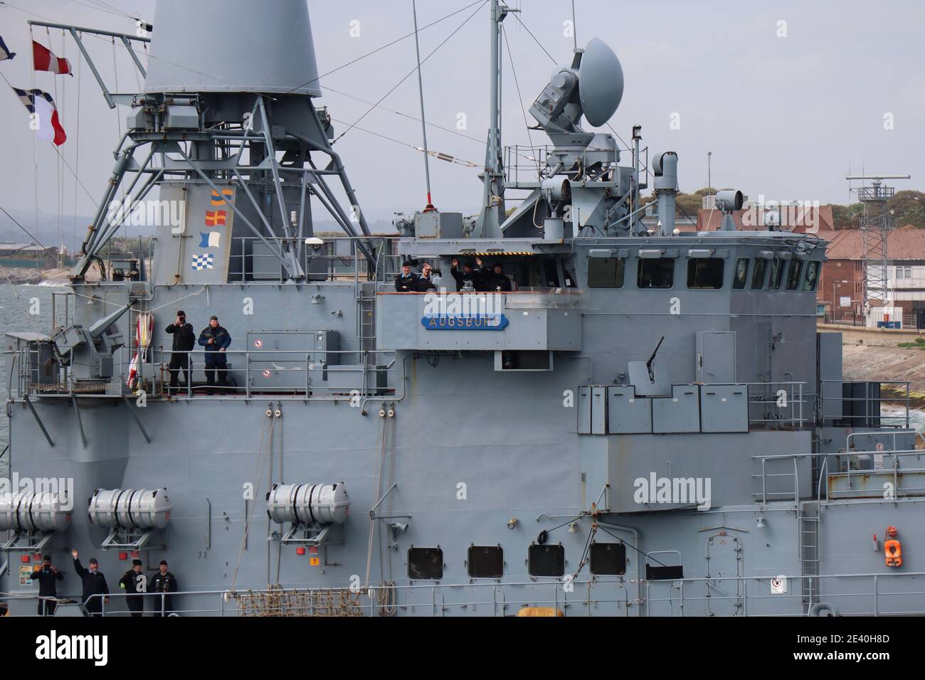 Crew on the German Naval ship FGS AUGSBURG wave to people watching the ...